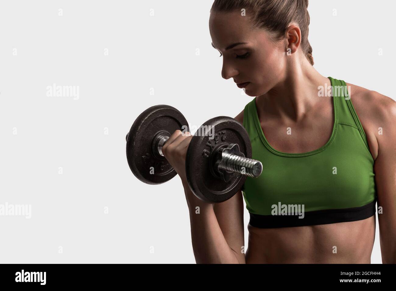 Beautiful young woman in a workout gear lifting dumbbells Stock Photo ...