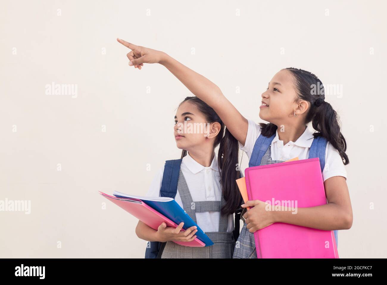 The two schoolgirls in uniform and holding folders looking up one of ...