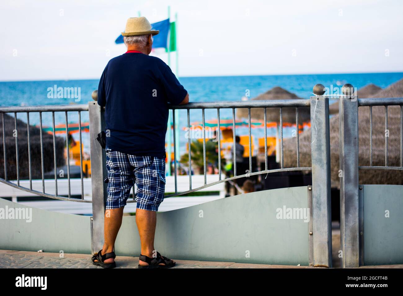 A back view of a senior man resting at the resort and watching the ...