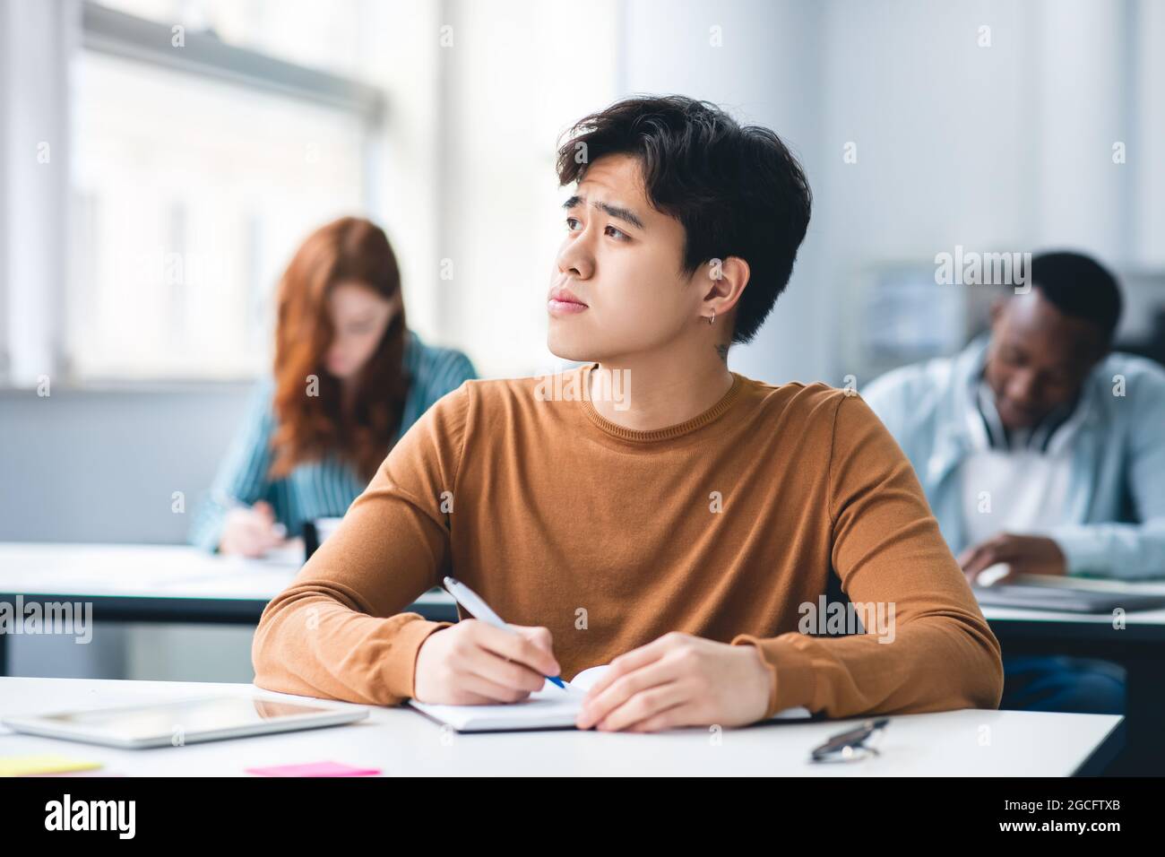 Studying And Learning Concept. Portrait of pensive asian male student ...