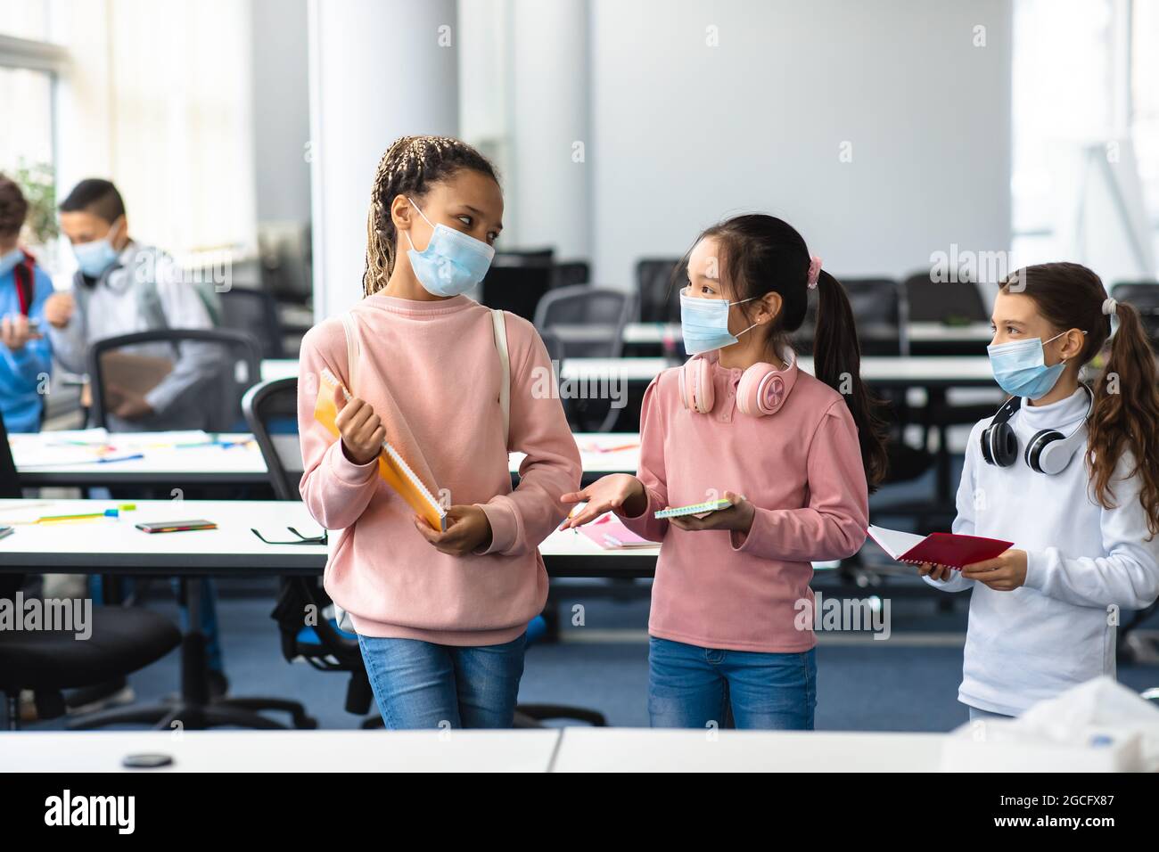 Portrait of multicultural girls standing in auditorium and talking ...