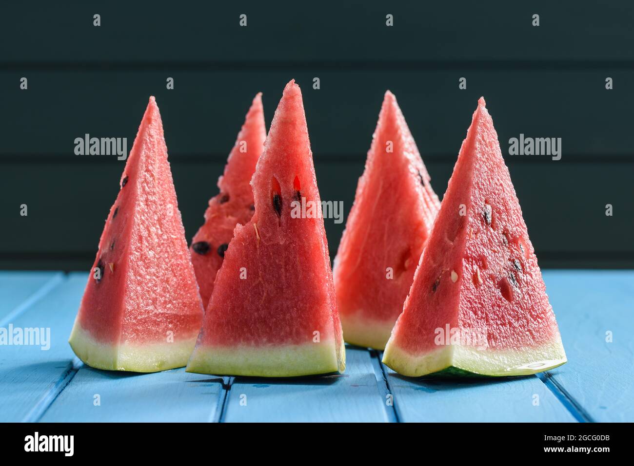 Bright red juicy watermelon cut into high triangles standing on blue table closeup Stock Photo ...