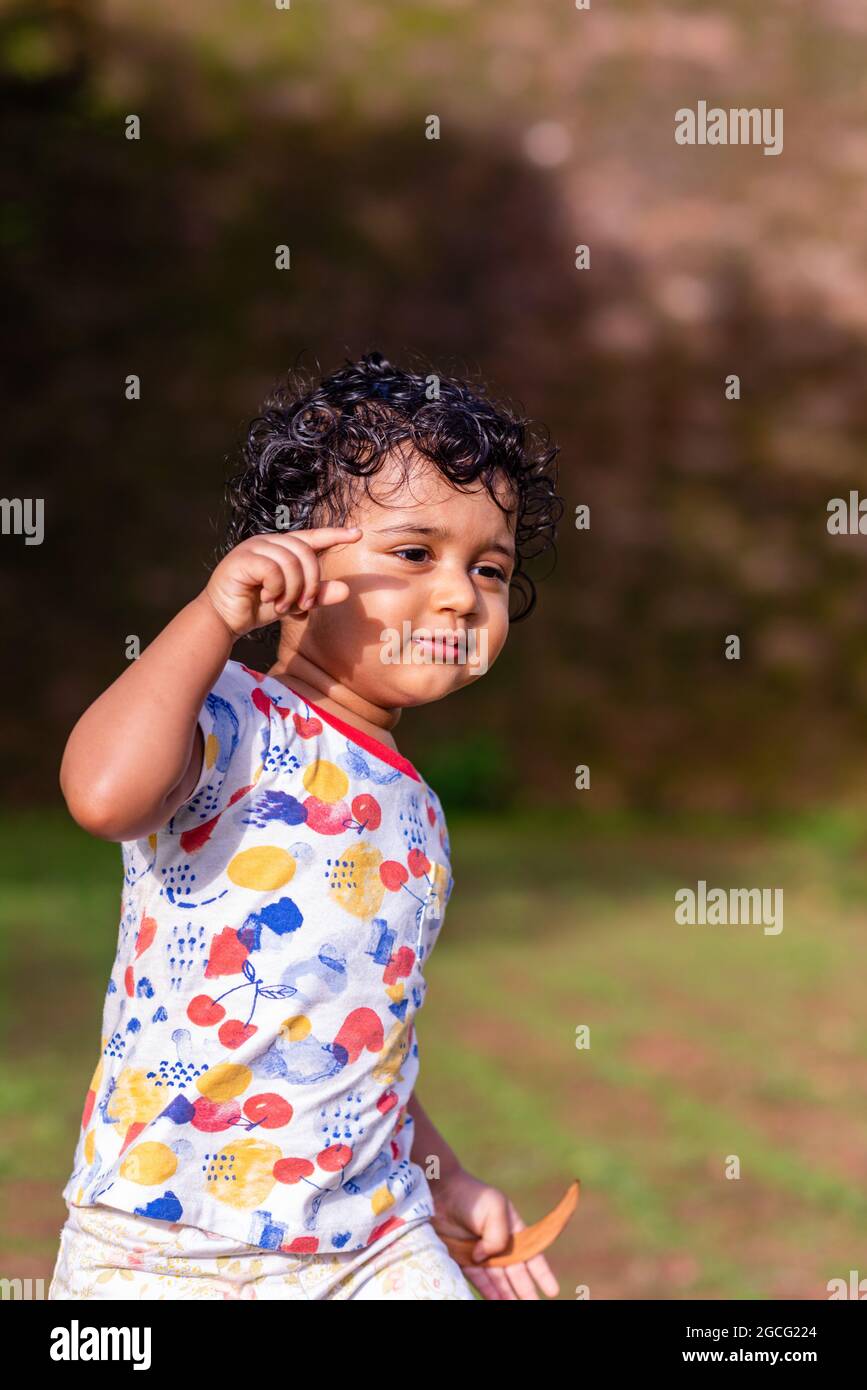 A vertical shot of an Indian small boy with curly hair playing outdoors in the park Stock Photo ...