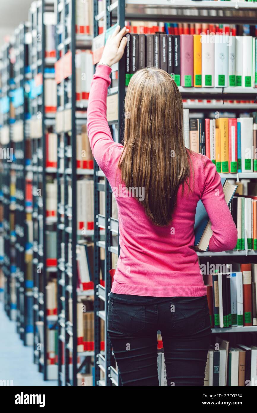 Student in college library reading a book Stock Photo - Alamy