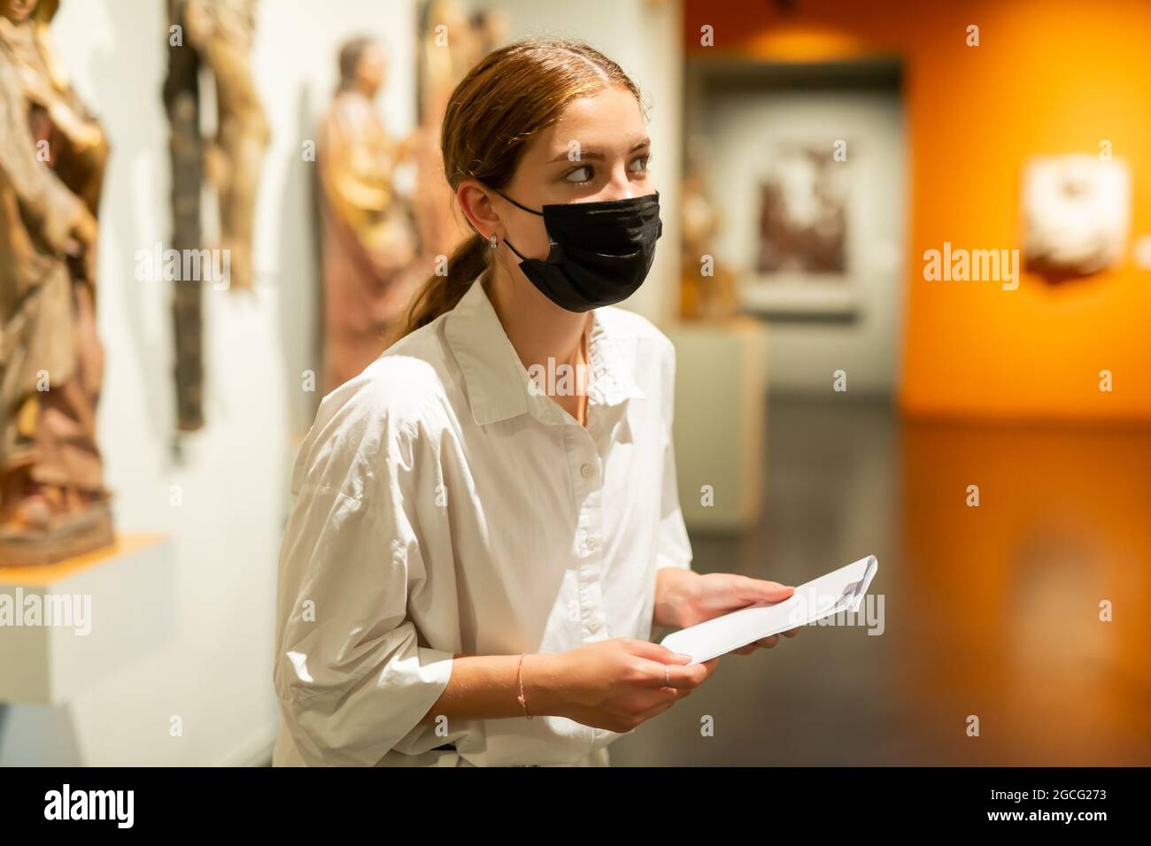 Woman wearing face mask observing artworks in museum Stock Photo - Alamy