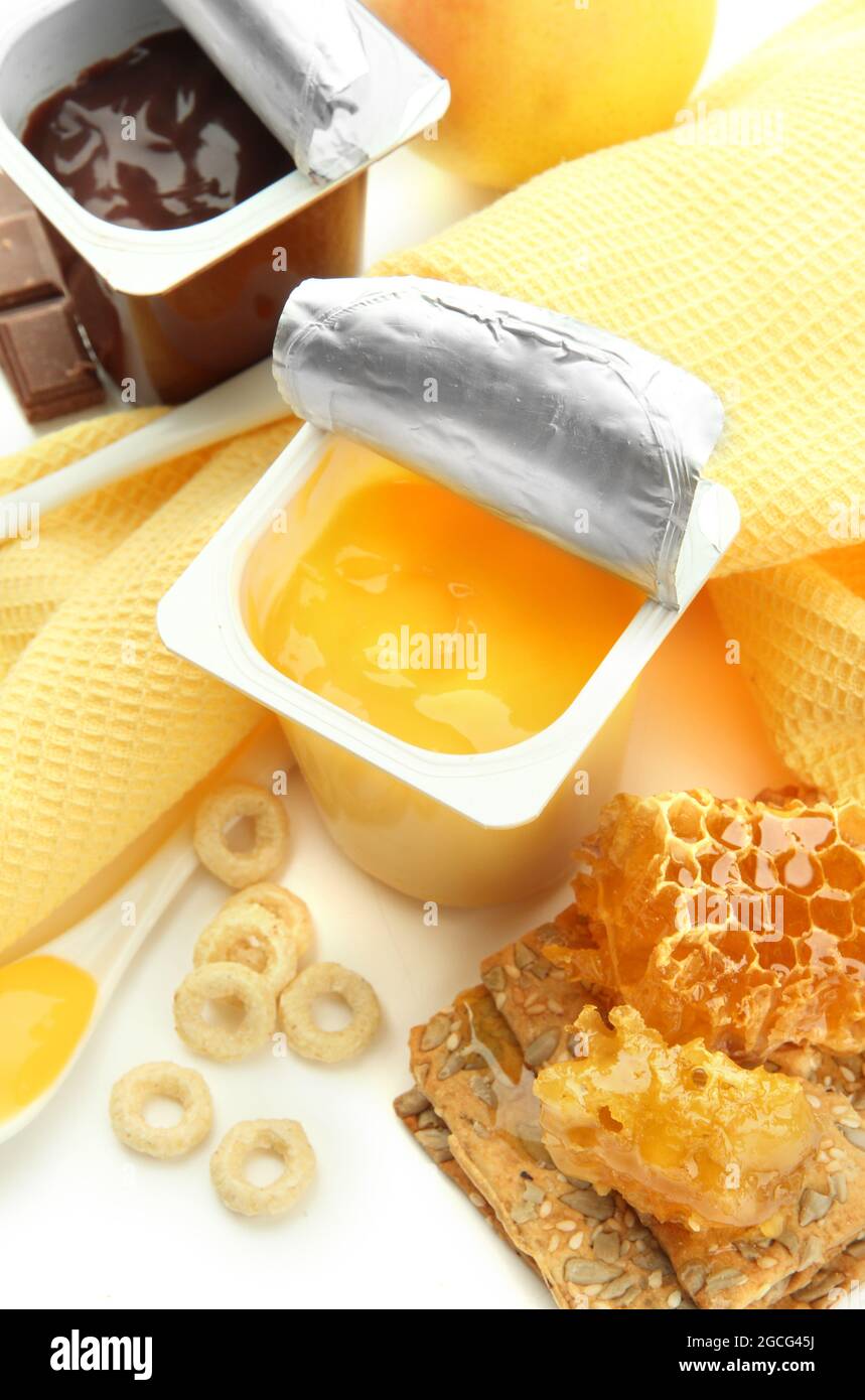 Tasty desserts in open plastic cups and honey combs, fruits and flakes ...