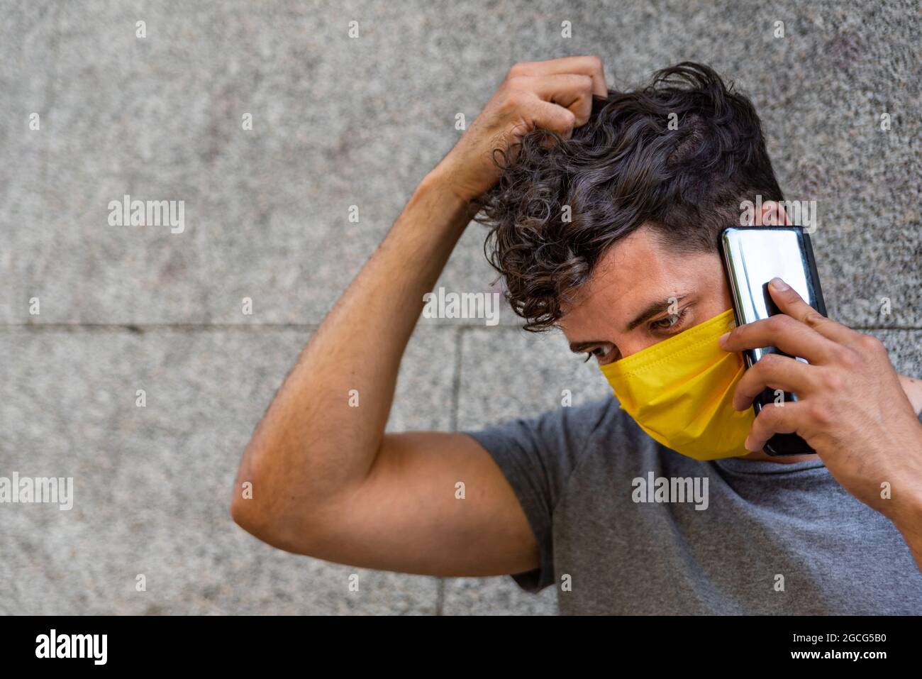 Young latin man with face mask using phone Stock Photo - Alamy