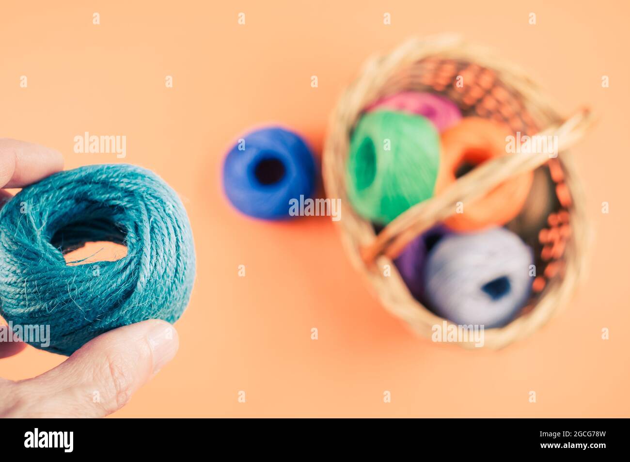 A closeup shot of male hand holding a green textile ball of wool with a ...