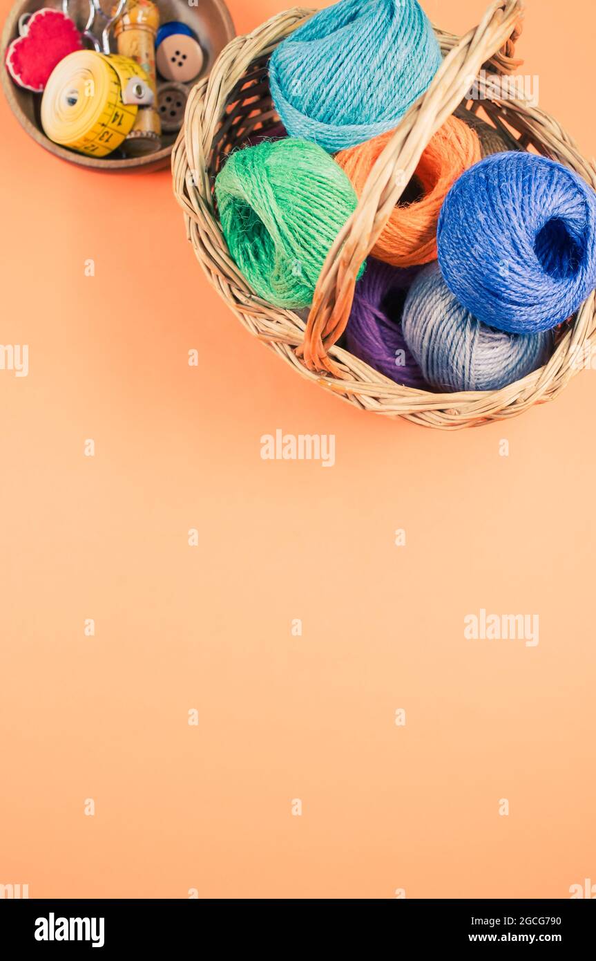 A pile of colorful textile balls of wool in a wicker basket on orange ...