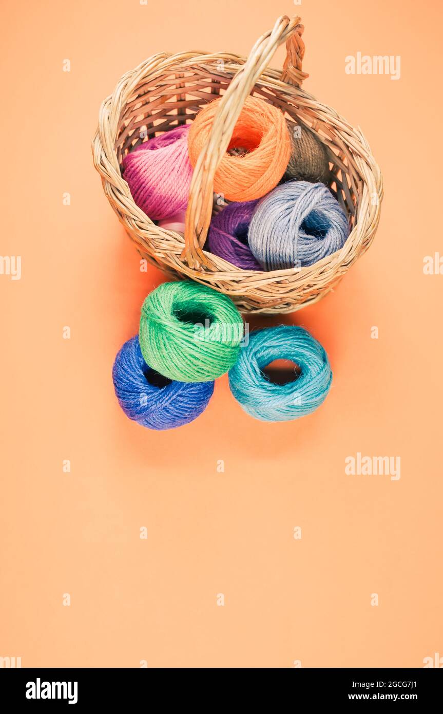 A pile of colorful textile balls of wool in a wicker basket on orange ...
