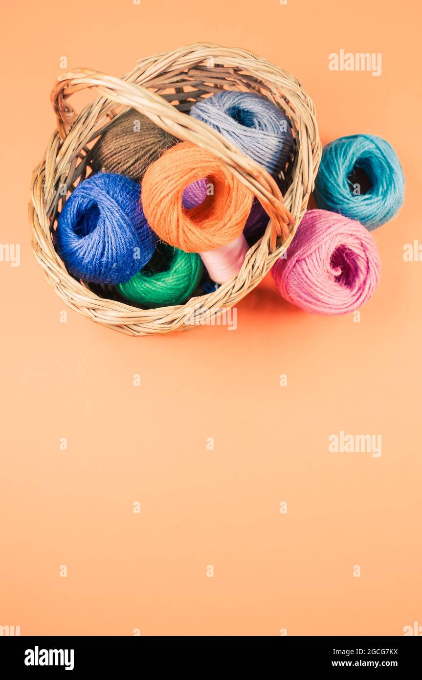 A pile of colorful textile balls of wool in a wicker basket on orange ...