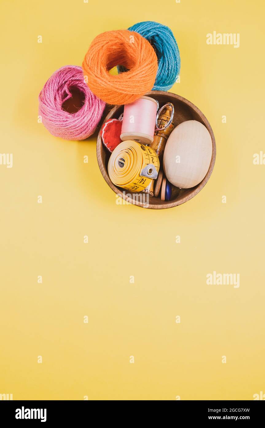 A bowl of sewing accessories and colorful textile balls of wool on ...