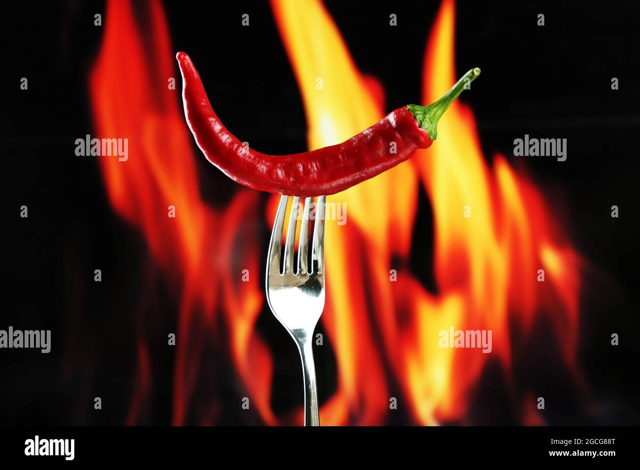 Red hot chili pepper on fork, on fire background Stock Photo - Alamy