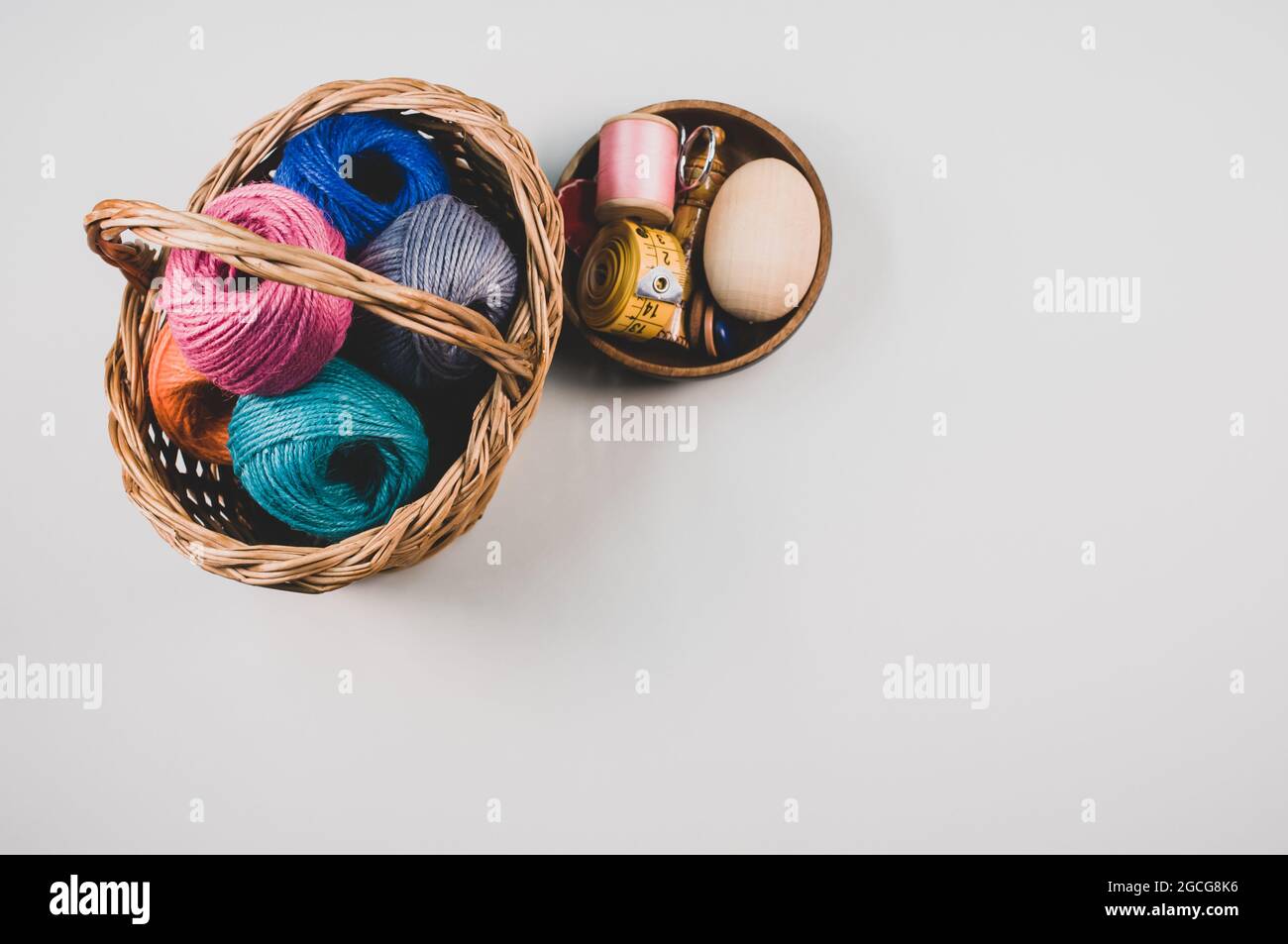 A pile of colorful textile balls of wool in a wicker basket on gray ...