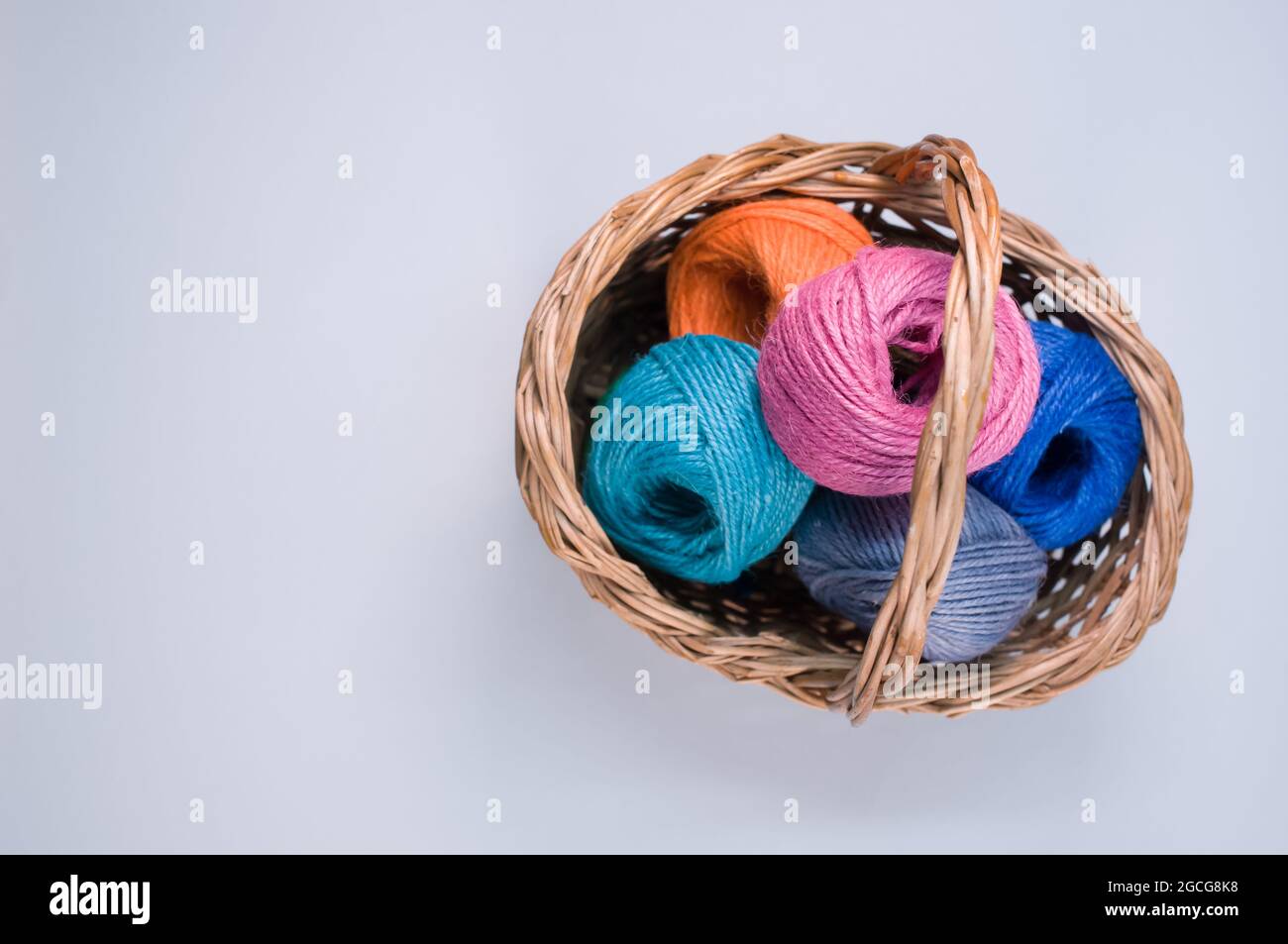 A pile of colorful textile balls of wool in a wicker basket on blue ...