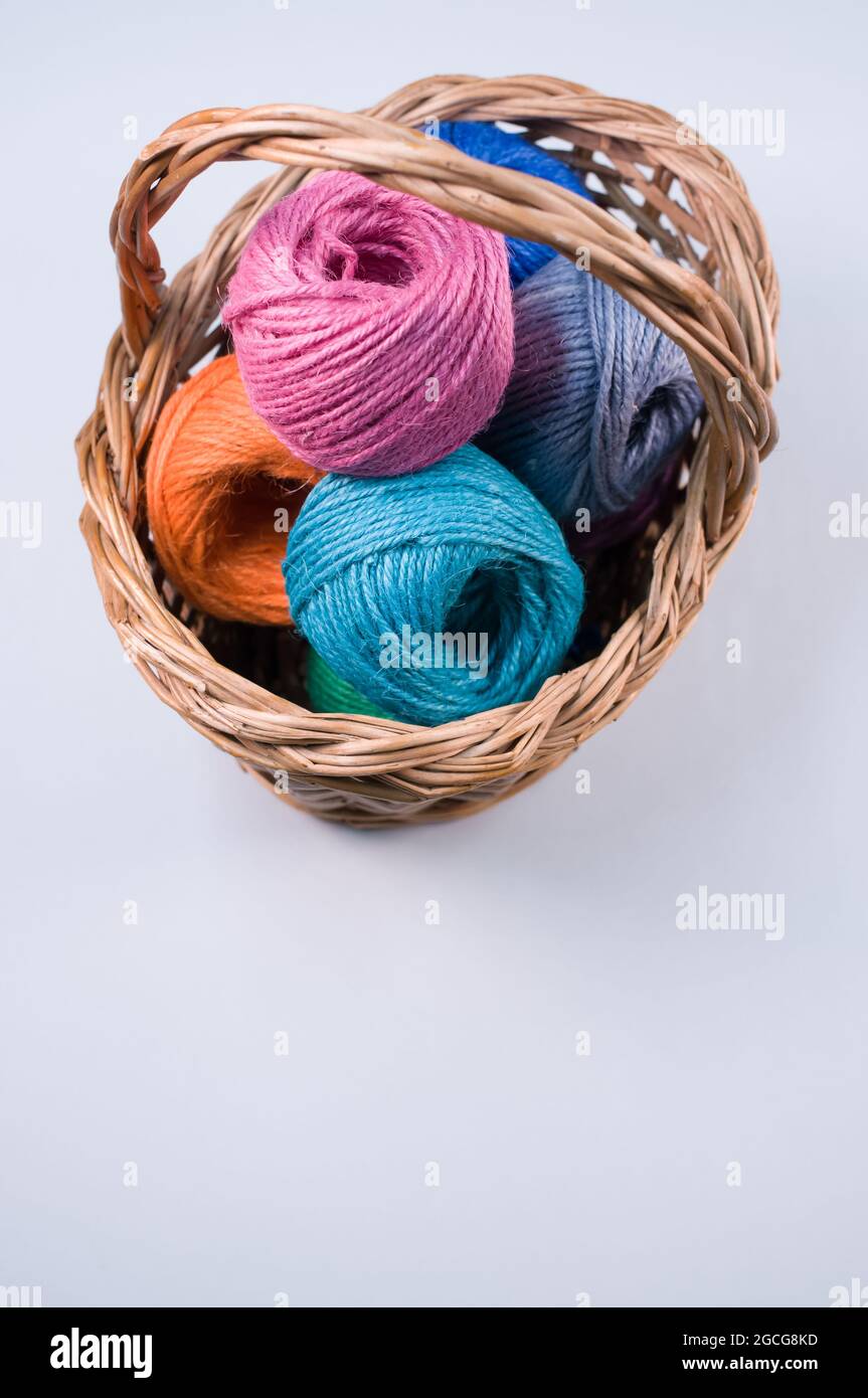 A pile of colorful textile balls of wool in a wicker basket on blue ...