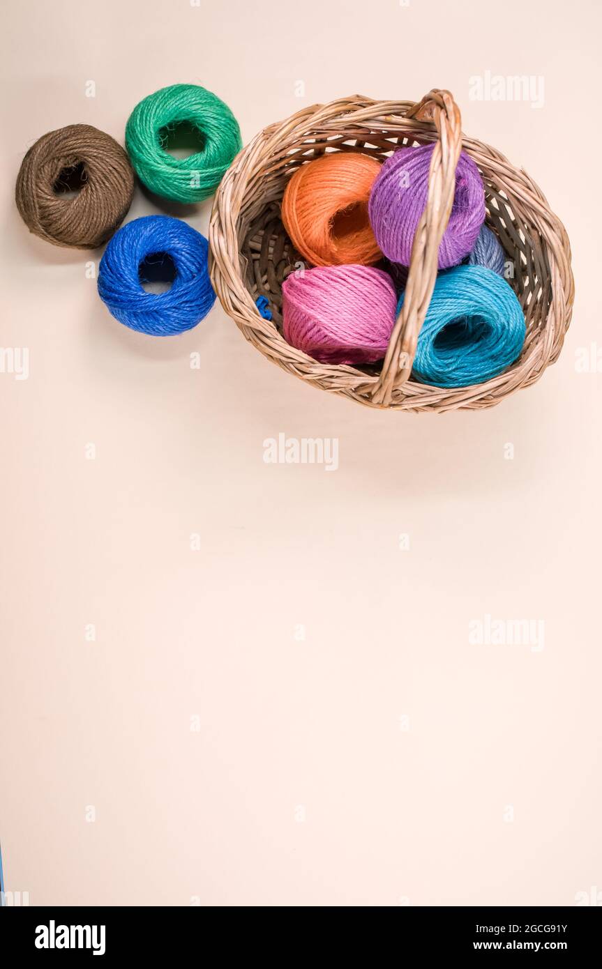 A pile of colorful textile balls of wool in a wicker basket on brown ...
