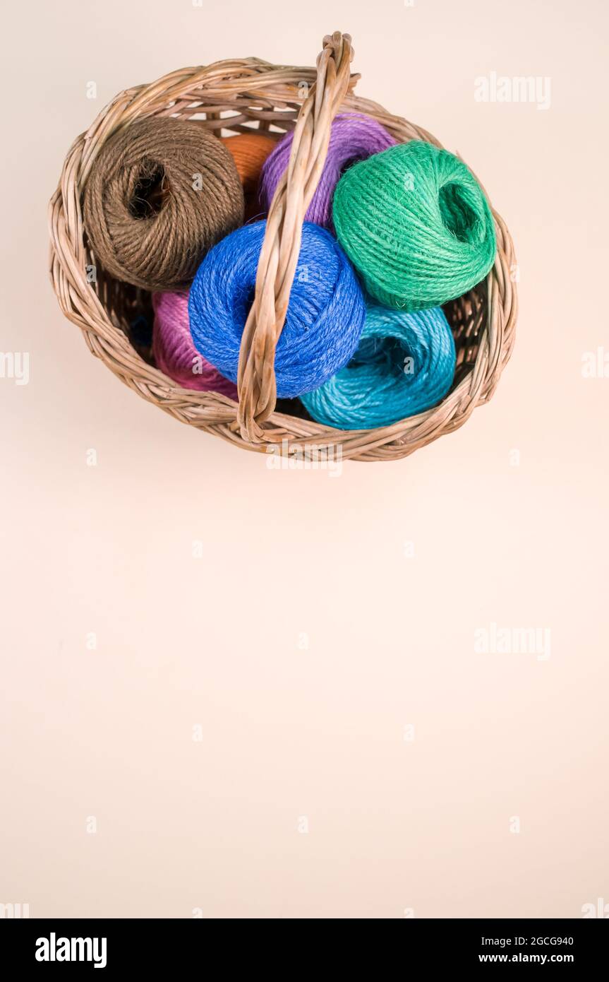 A pile of colorful textile balls of wool in a wicker basket on brown ...