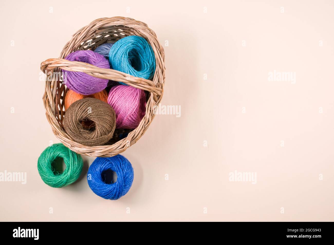 A pile of colorful textile balls of wool in a wicker basket on brown ...