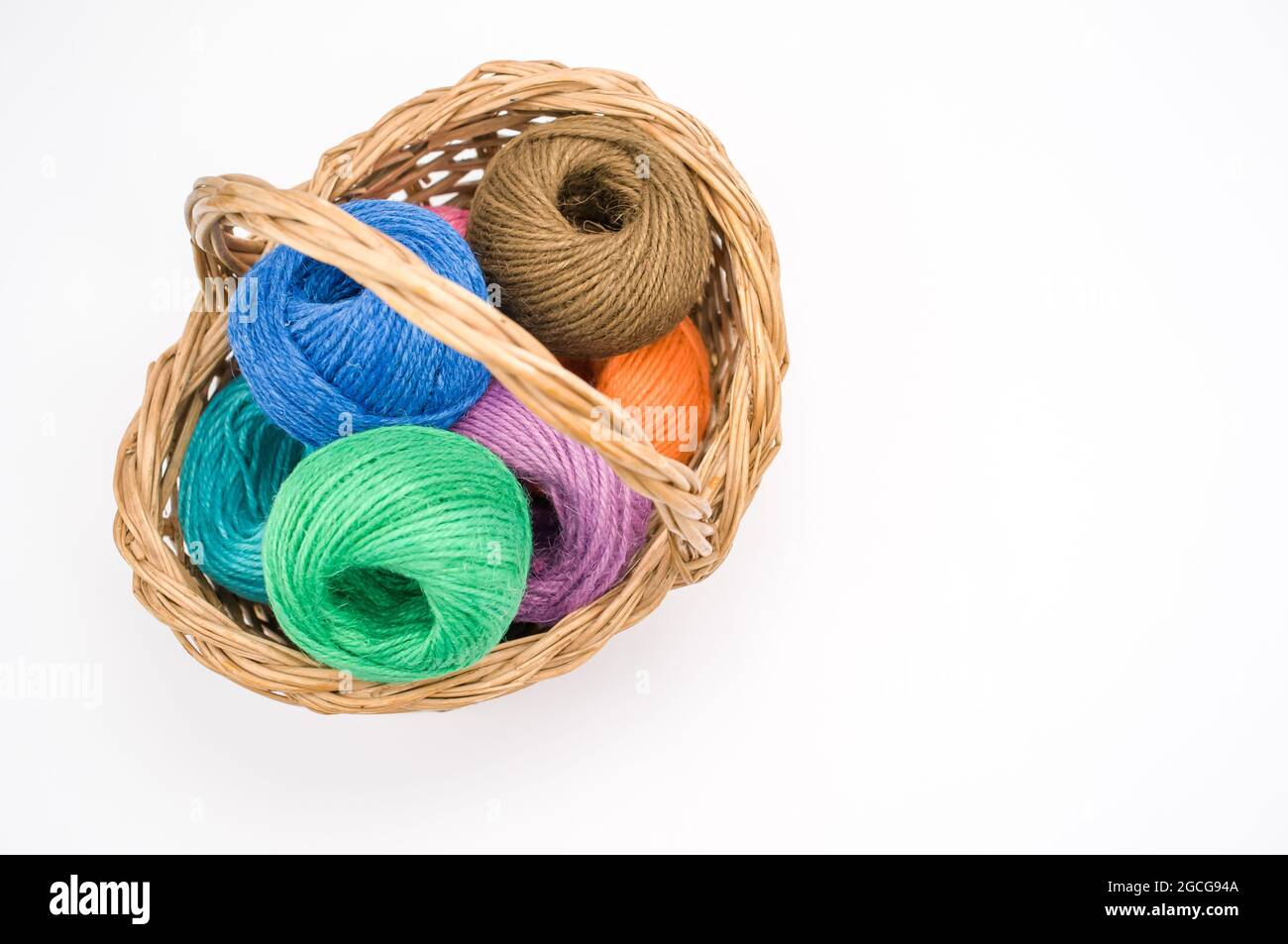 A pile of colorful textile balls of wool in a wicker basket on white ...