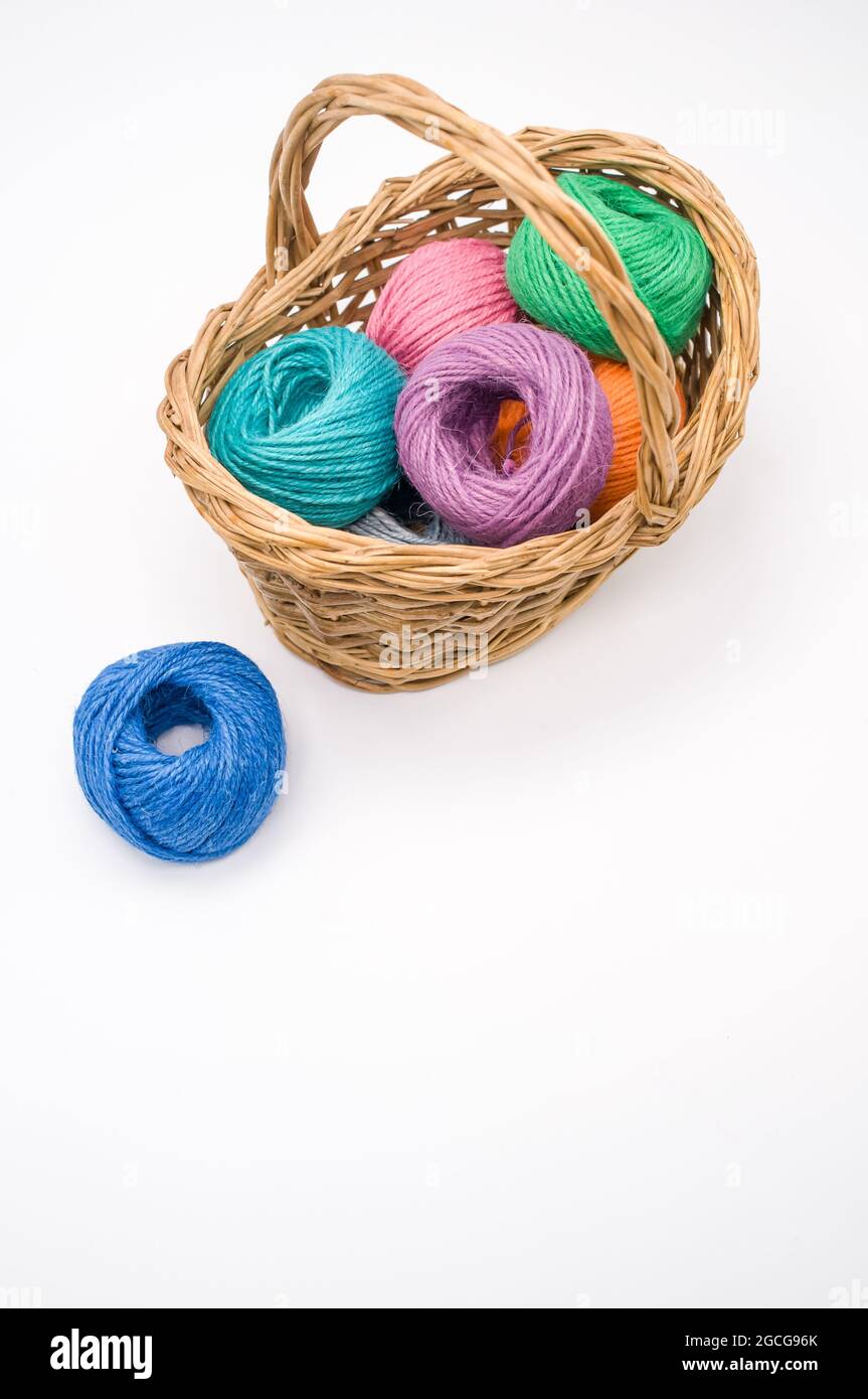 A pile of colorful textile balls of wool in a wicker basket on white ...