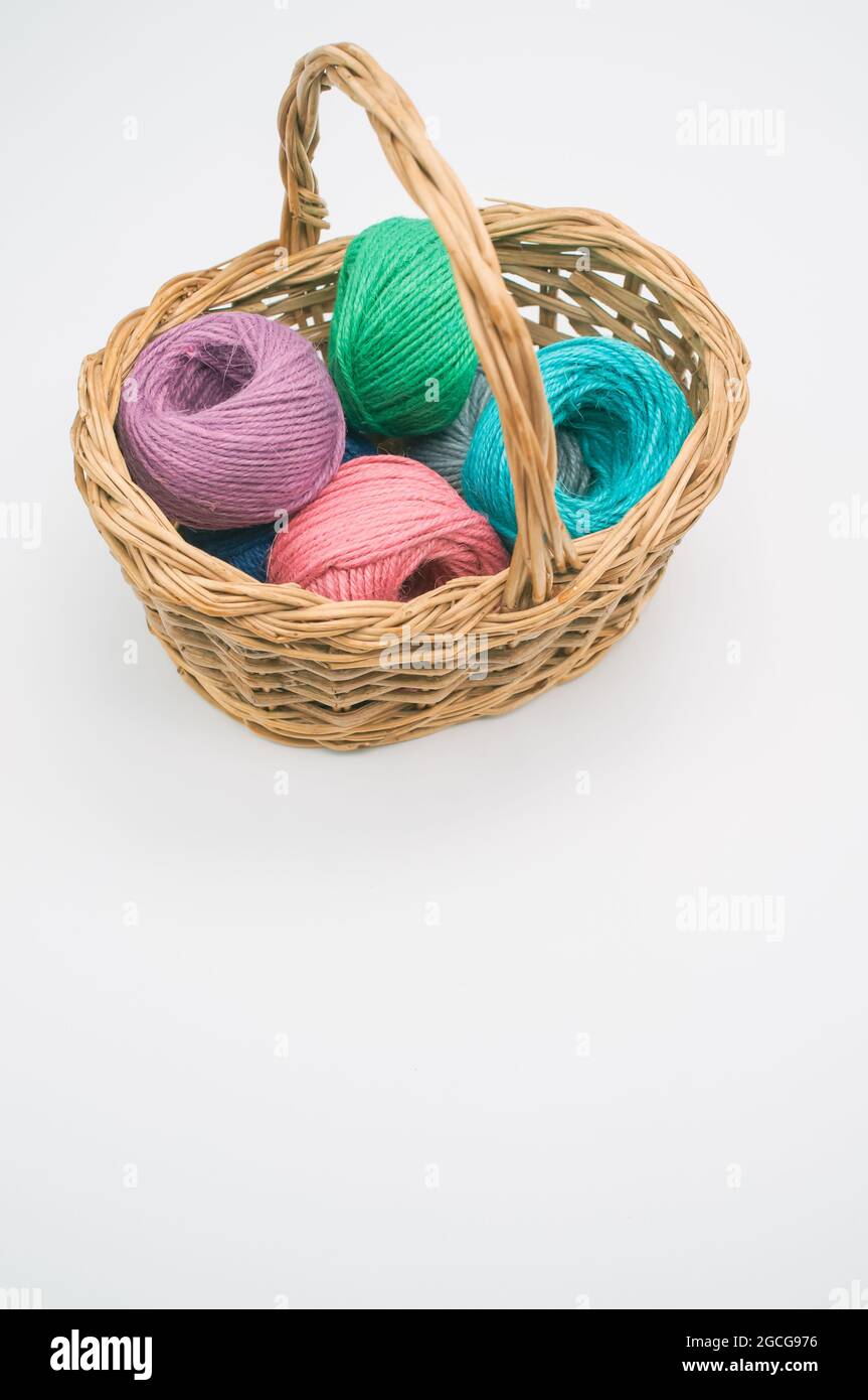 A pile of colorful textile balls of wool in a wicker basket on white ...