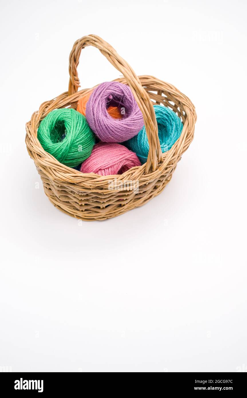 A pile of colorful textile balls of wool in a wicker basket on white ...