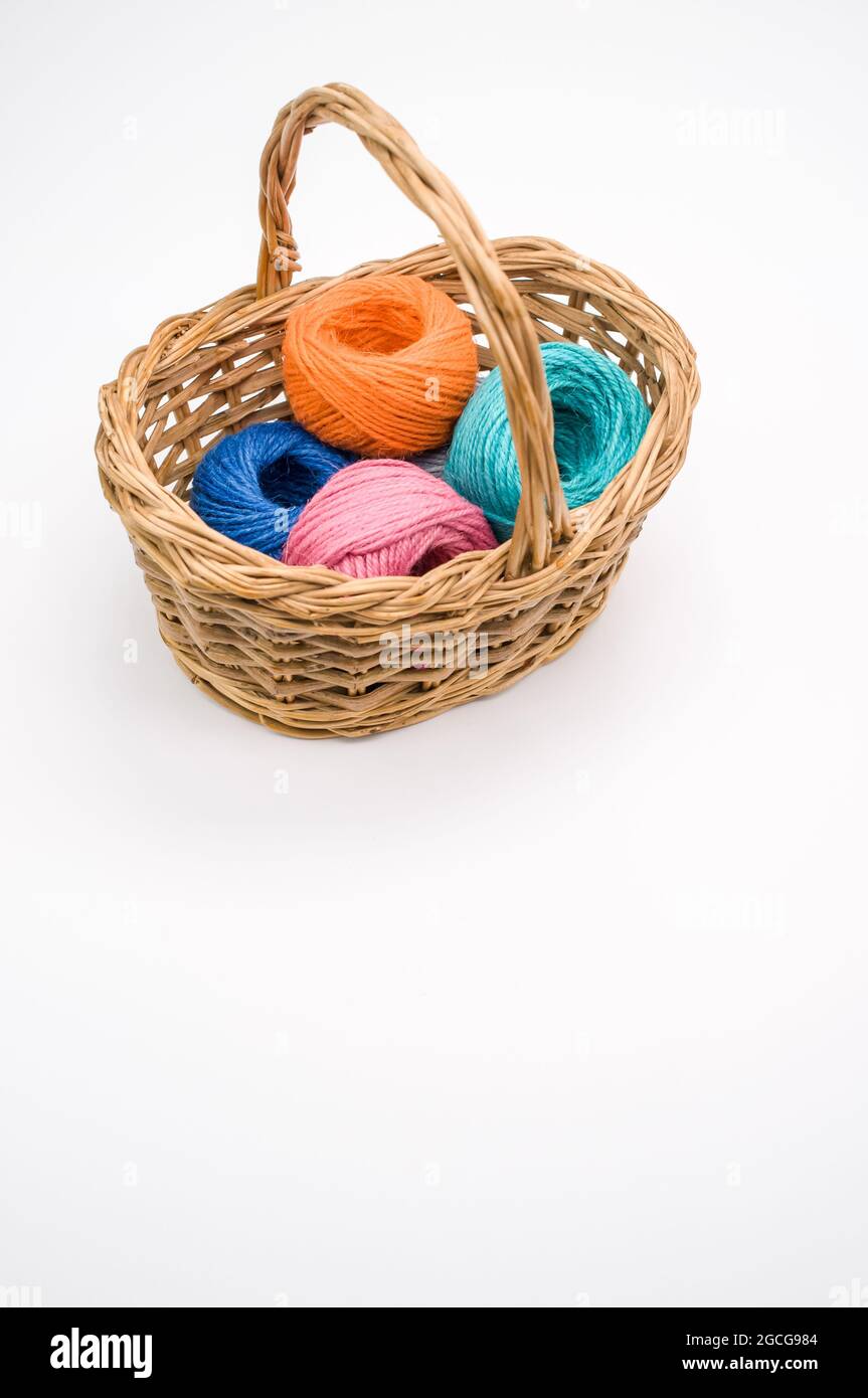 A pile of colorful textile balls of wool in a wicker basket on white ...
