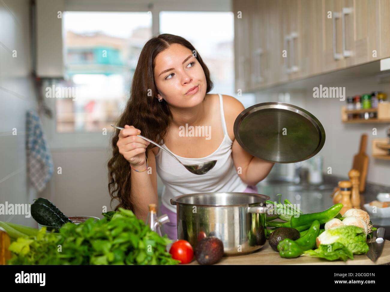 Young confused woman decides what to cook in kitchen Stock Photo - Alamy