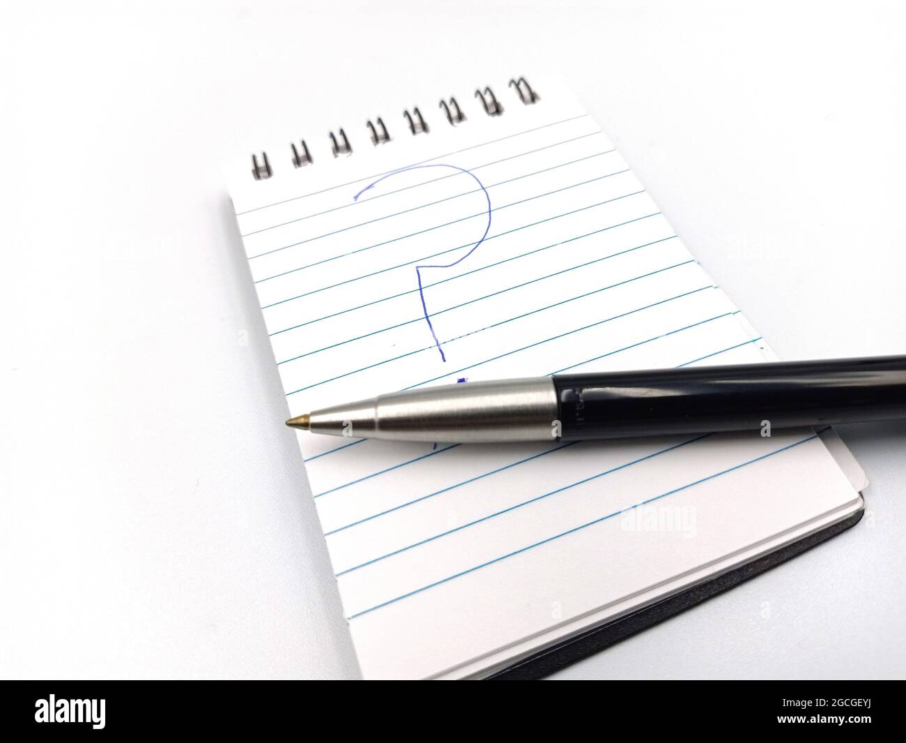 Closeup shot of a small open notebook and pen with a written question ...