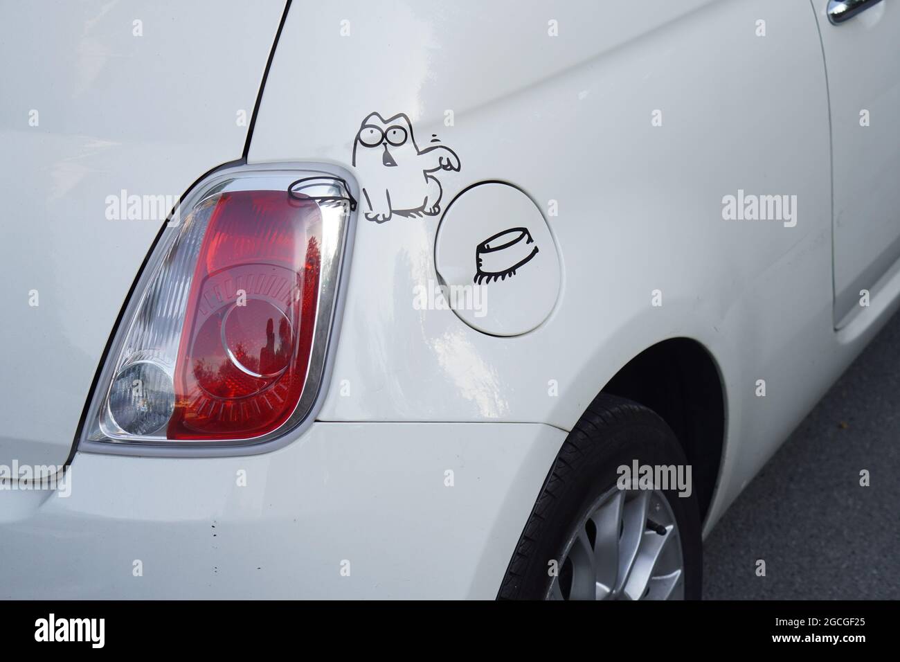 Funny cat sticker on the gas tank of a white modern car parked outdoors ...