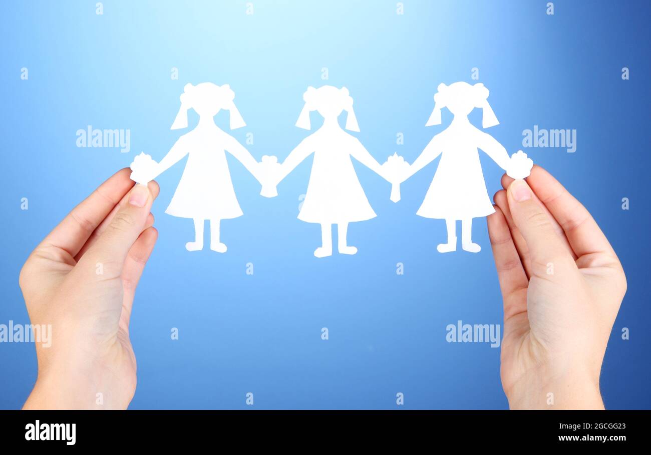 Paper people in hands on blue background Stock Photo - Alamy