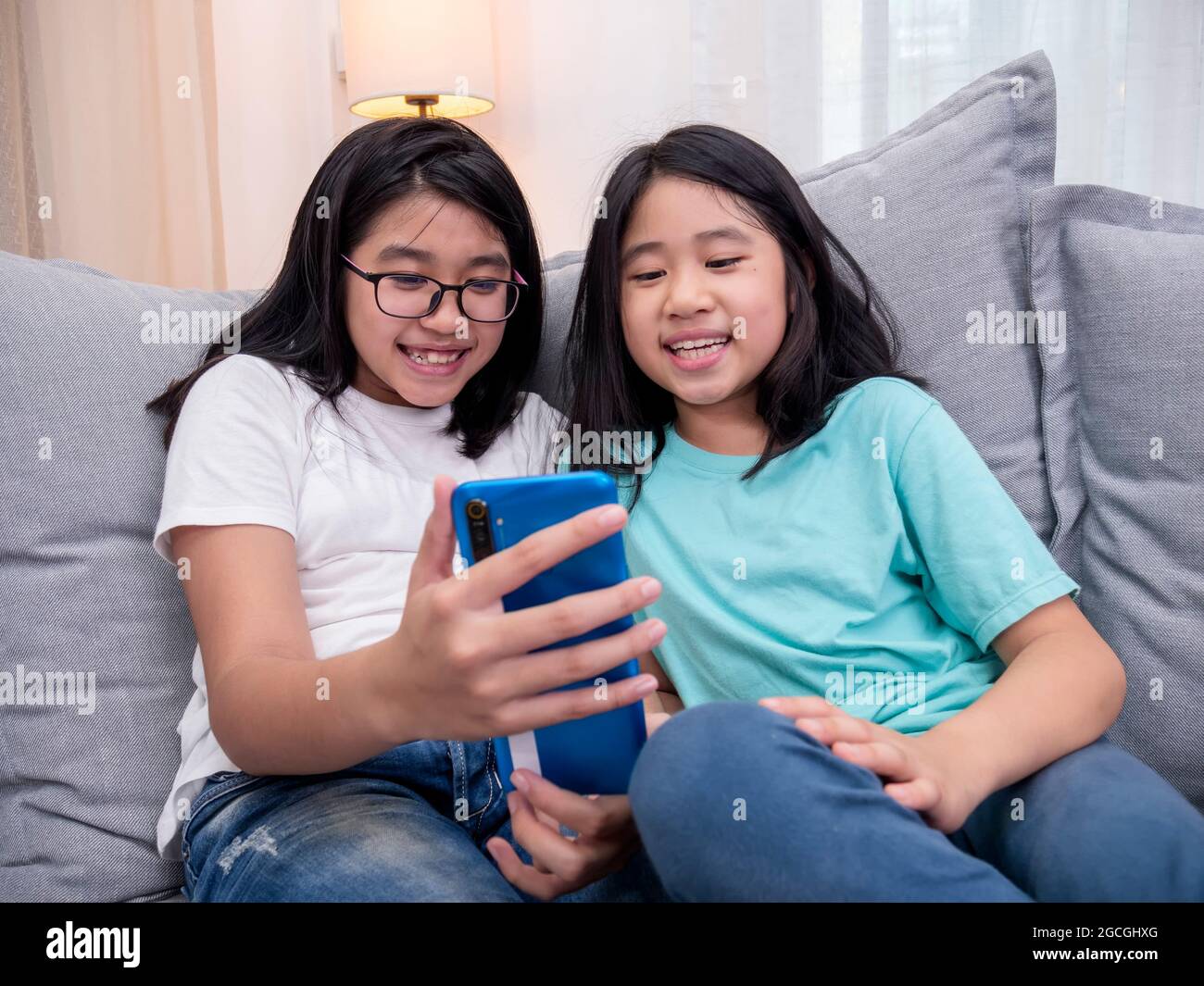 Happy siblings children sitting on sofa in living room speak with ...