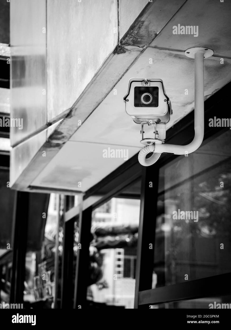 Old white CCTV camera hanging from modern concrete building, vertical ... Old white CCTV camera hanging from modern concrete building, vertical ...