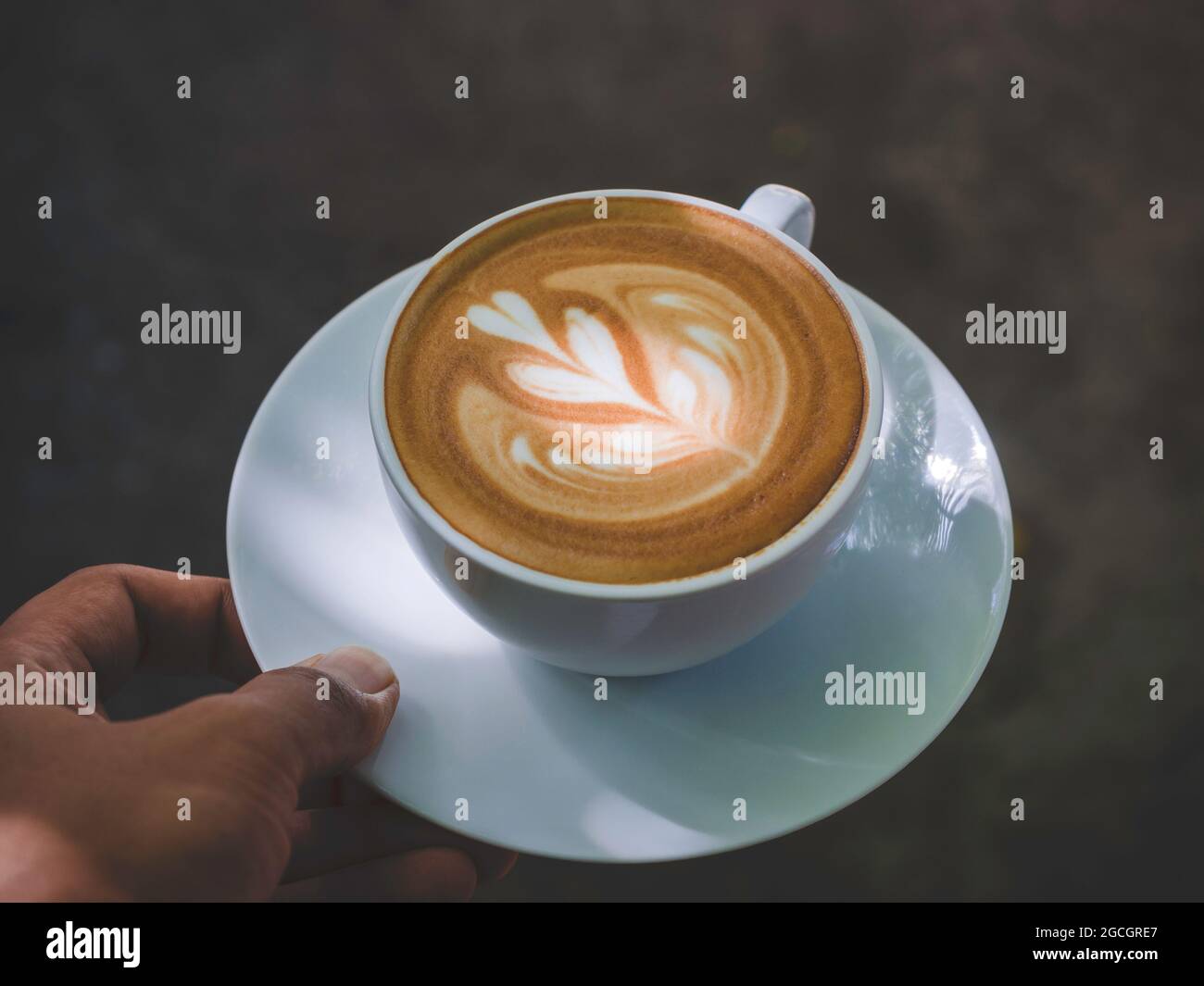 Latte art coffee cup in hand. Close up latte foam texture in cappucino ...