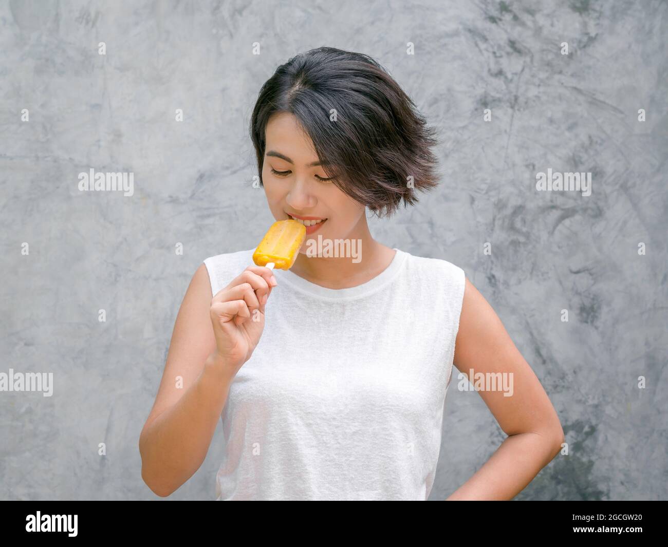 Women eating popsicles. Happy Asian woman short hair in casual white ...
