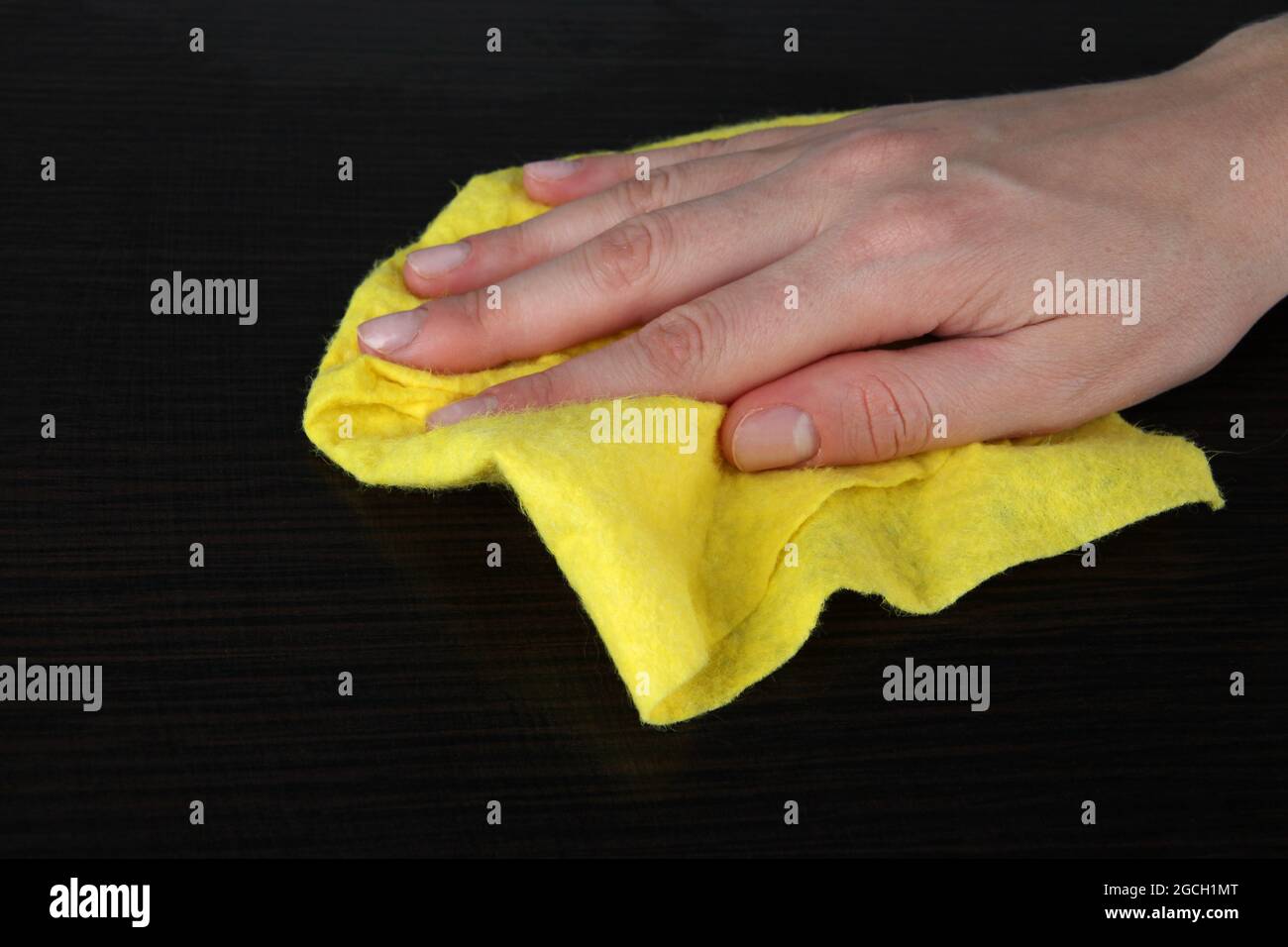 Hand wiping wooden surface with yellow rag Stock Photo - Alamy
