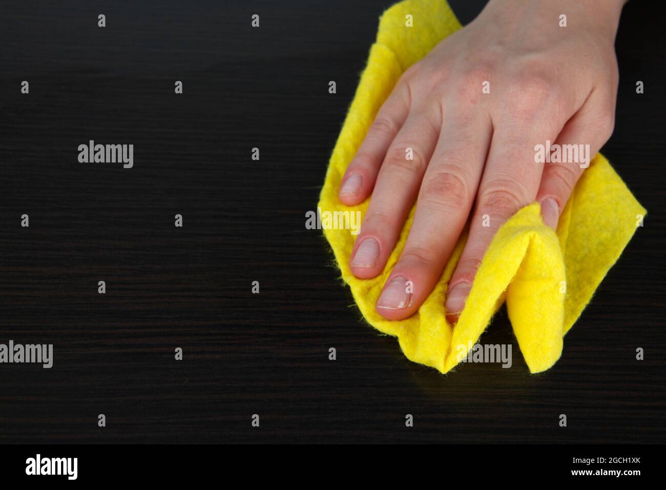 Hand wiping wooden surface with yellow rag Stock Photo - Alamy