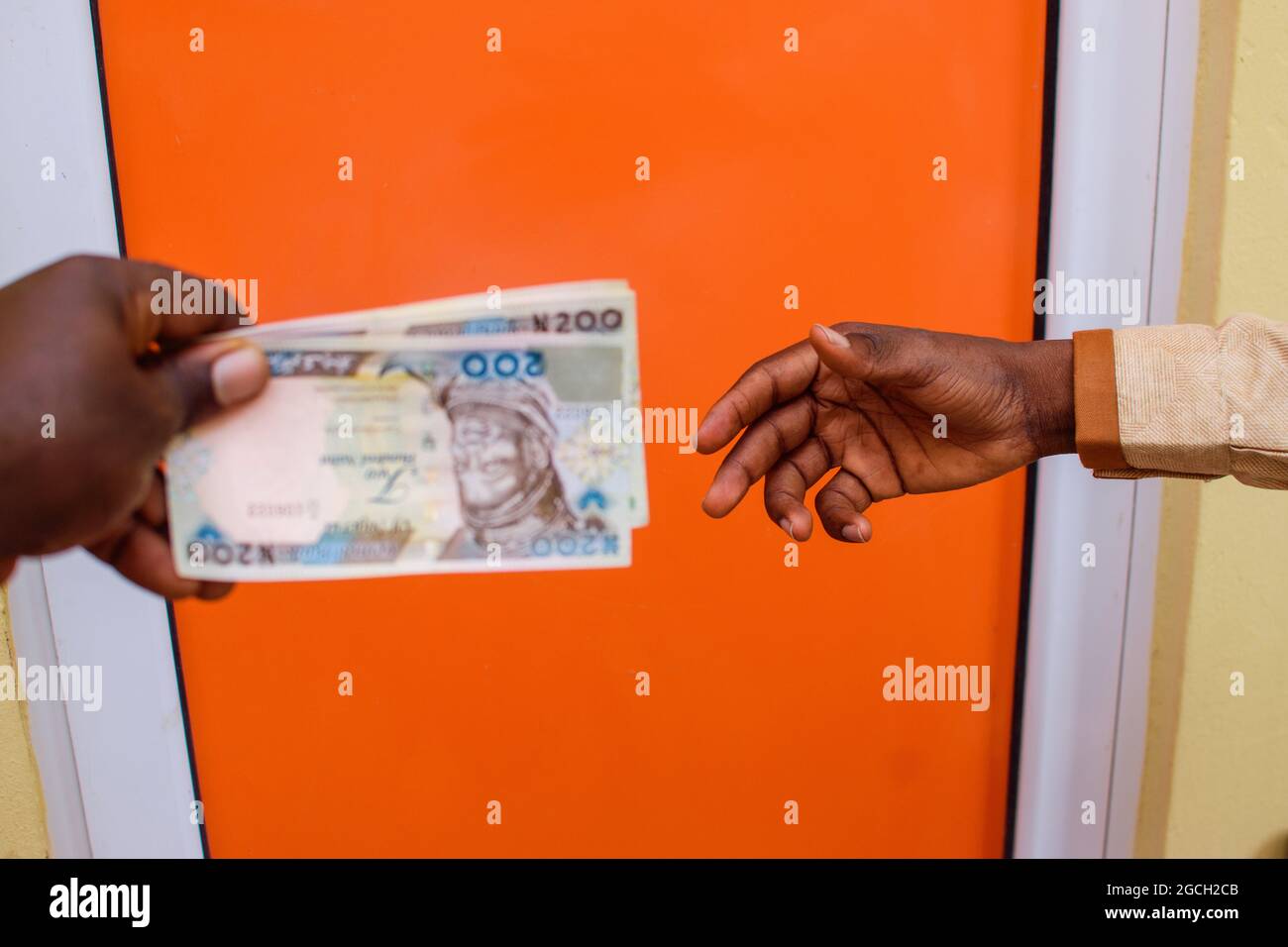Two African hands receiving or exchanging Nigerian Naira notes, cash or ...