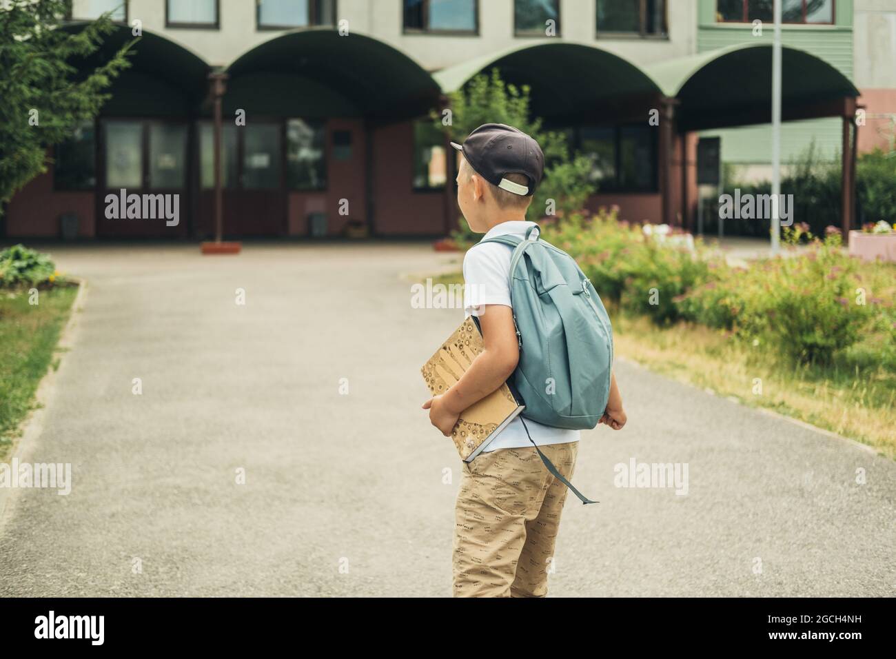 The boy, elementary school student, walking to school with bag behind ...