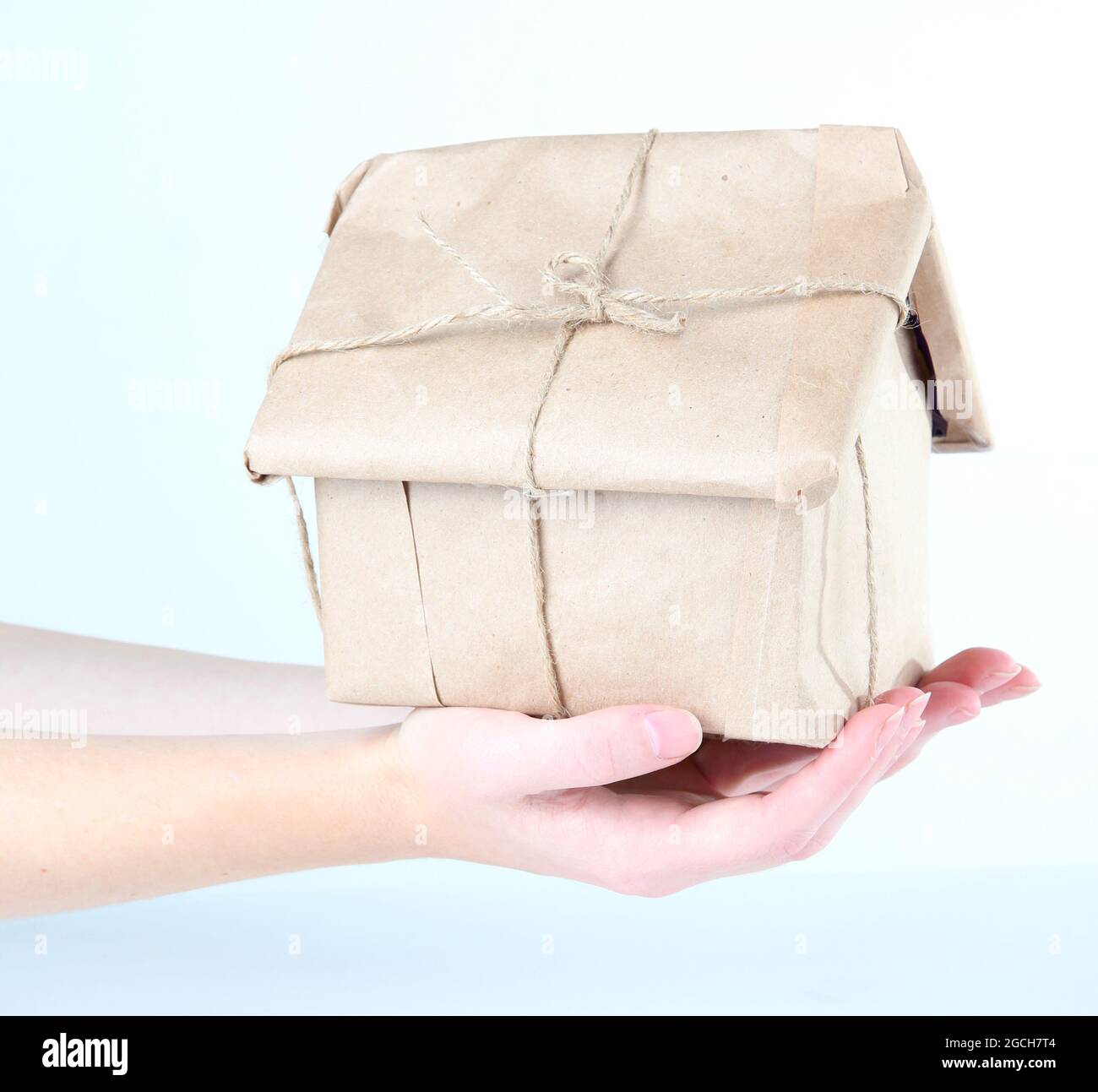 Woman hands holding a house wrapped in brown kraft paper, isolated on ...