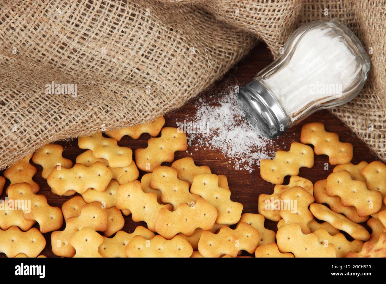 Delicious crackers with salt on wooden table on sackcloth background ...