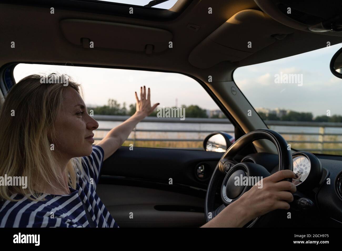 Calm woman driving car stretching hand in open window. Confident female ...