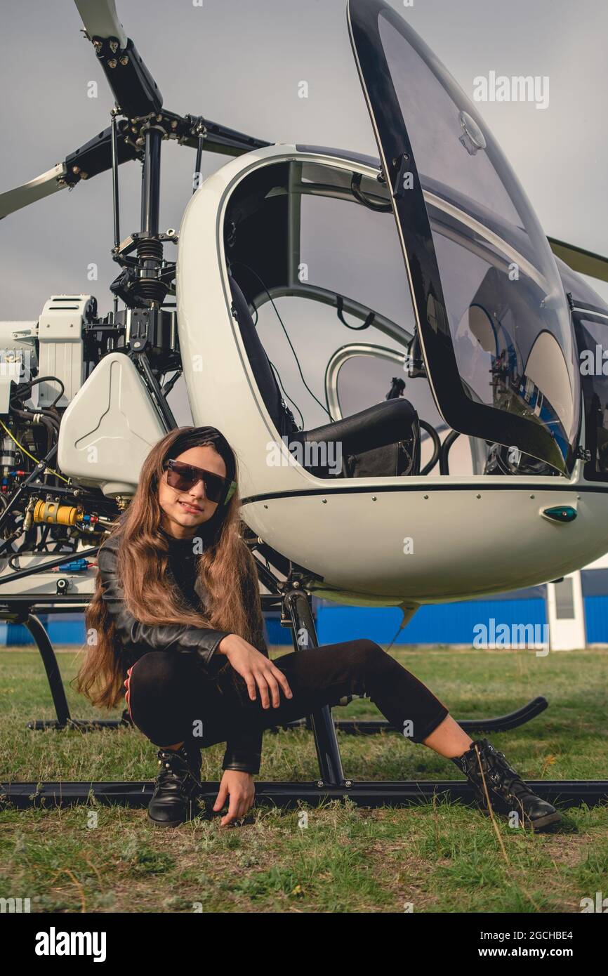 Smiling tween girl sitting near open helicopter on flying field Stock ...