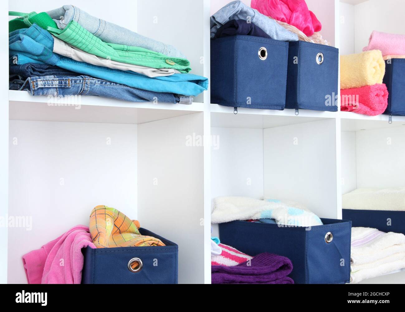 Blue textile boxes with towels and clothes in white shelves Stock Photo ...
