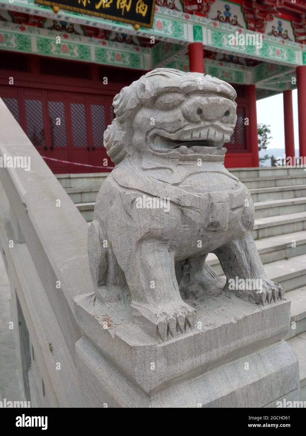 A stone lion dog guardian statue on a stairs banister at a replica ...