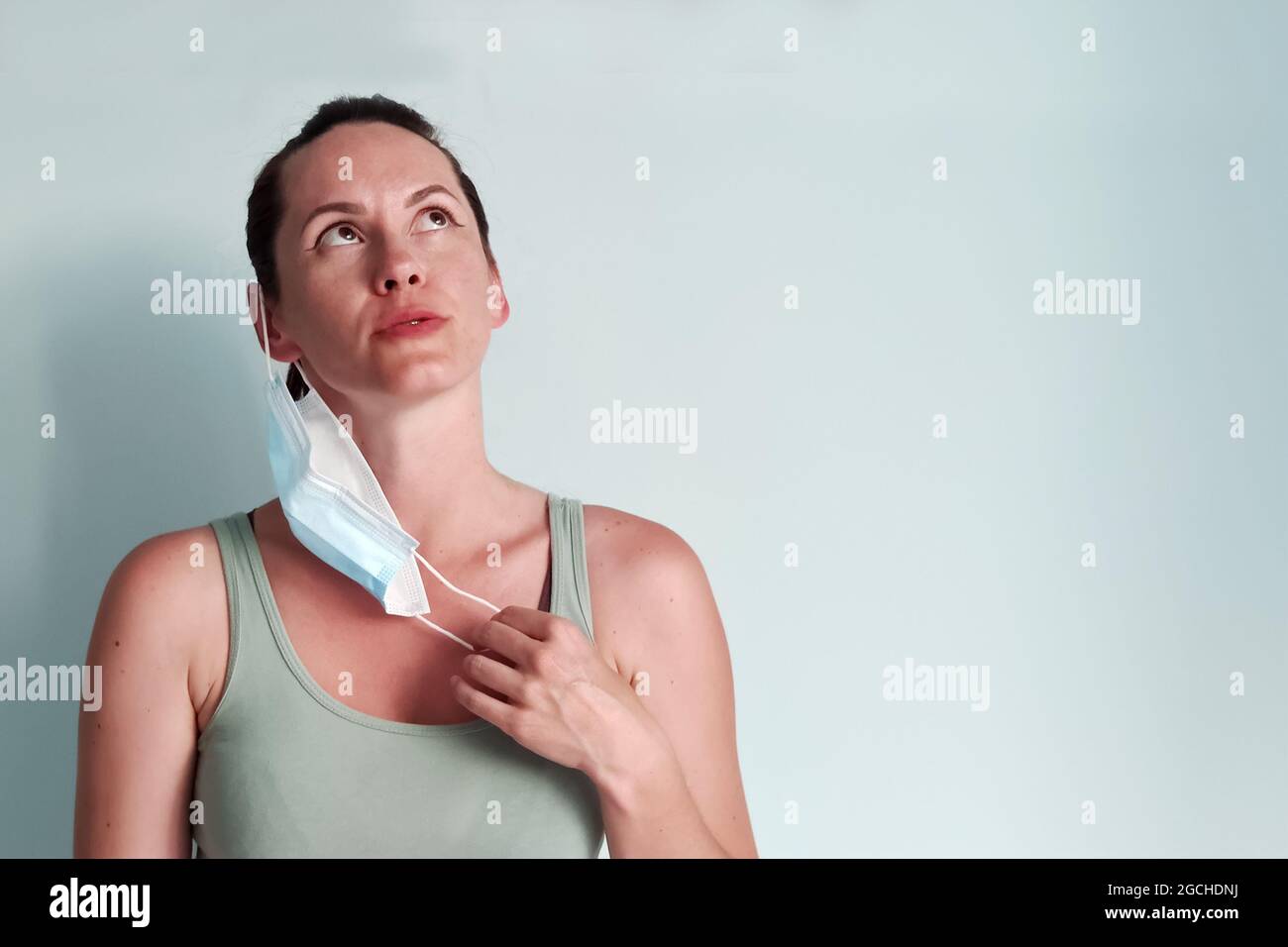 A young woman takes off her medical mask breathing in the air with ...