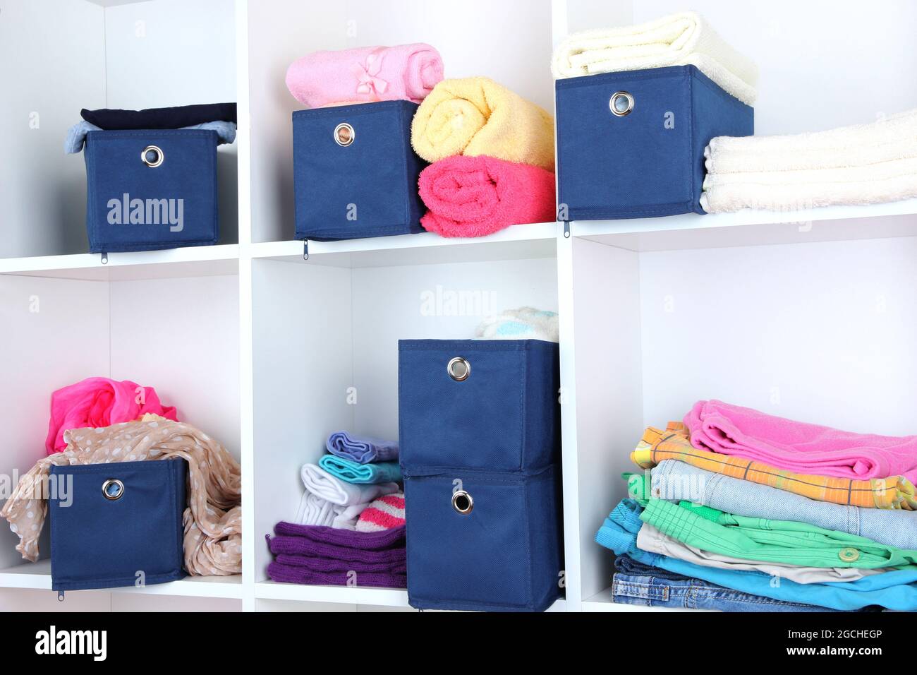 Blue textile boxes with towels and clothes in white shelves Stock Photo ...