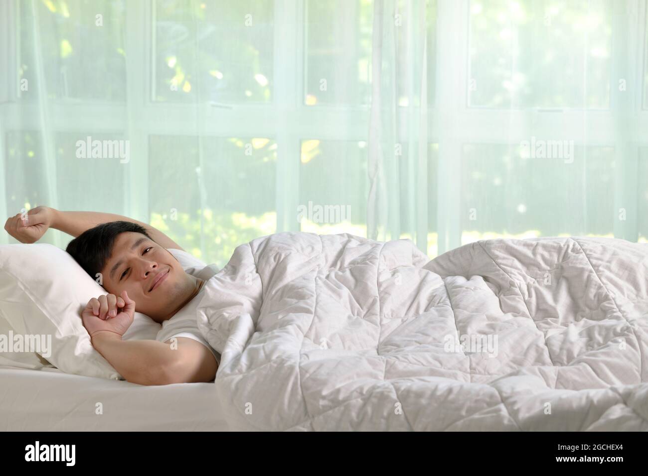 Asian man stretching in bed after wake up in the morning Stock Photo ...