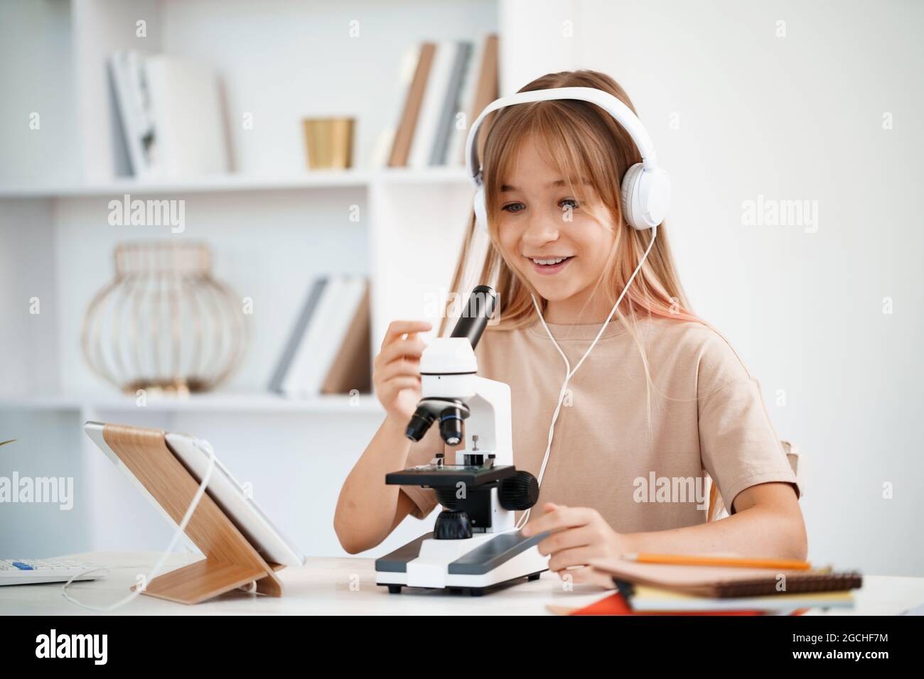 Young girl using microscope during online lesson education at home ...